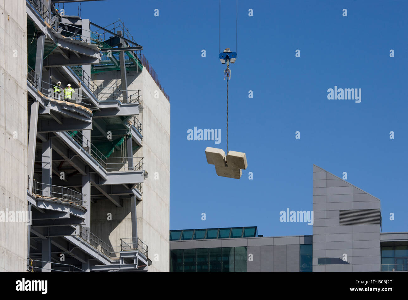 load being delivered by crane on construction site with onlookers in ...