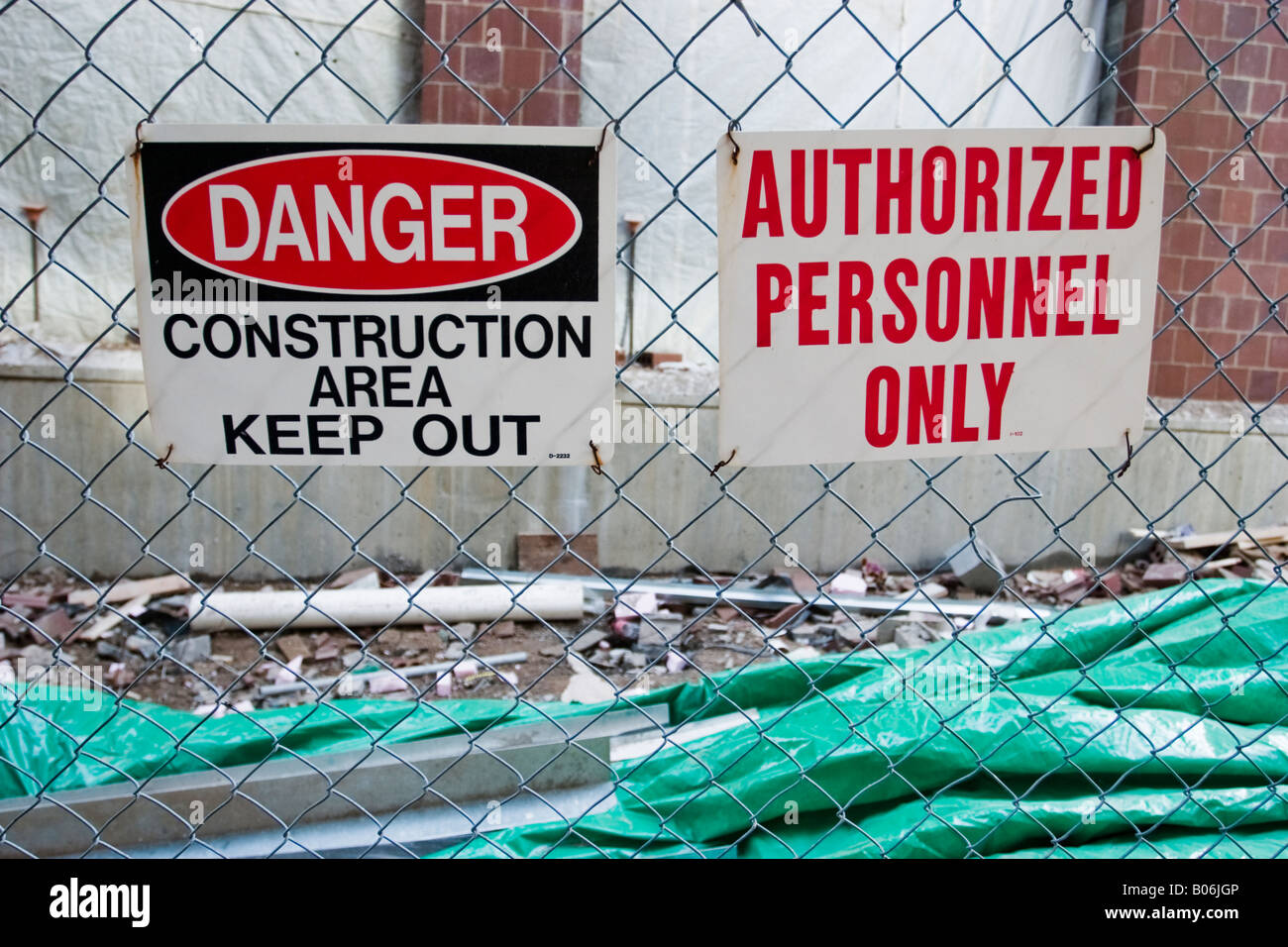 Two signs on fence at a construction site reading, "DANGER ...