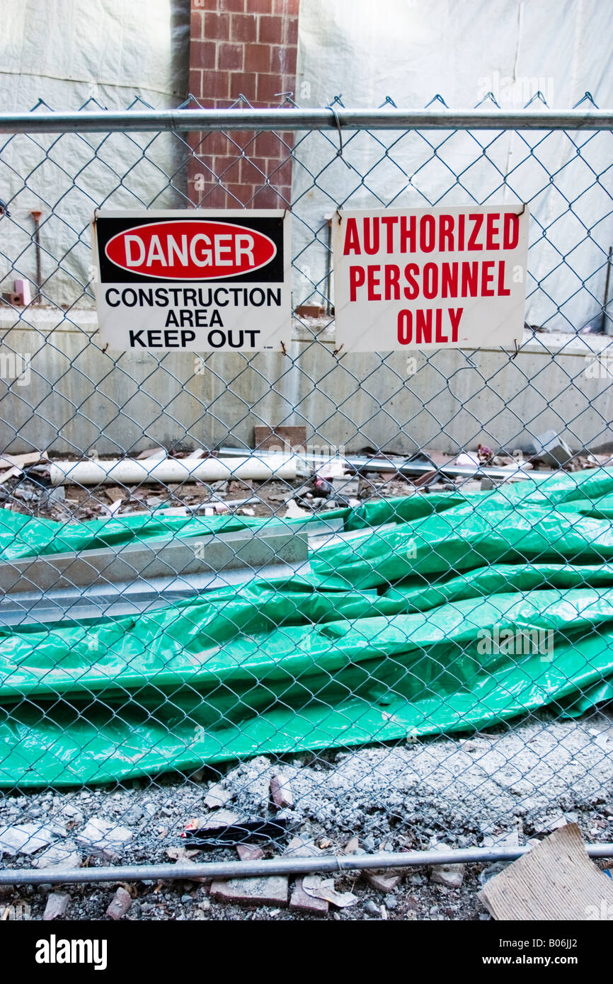 Two signs on fence at a construction site reading, "DANGER ...
