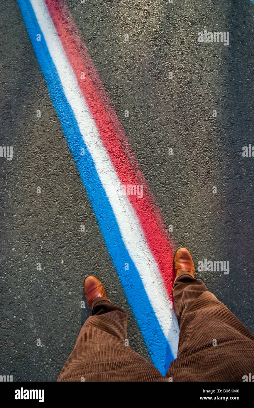 Close up of a man s legs and feet straddling red white and blue lines ...