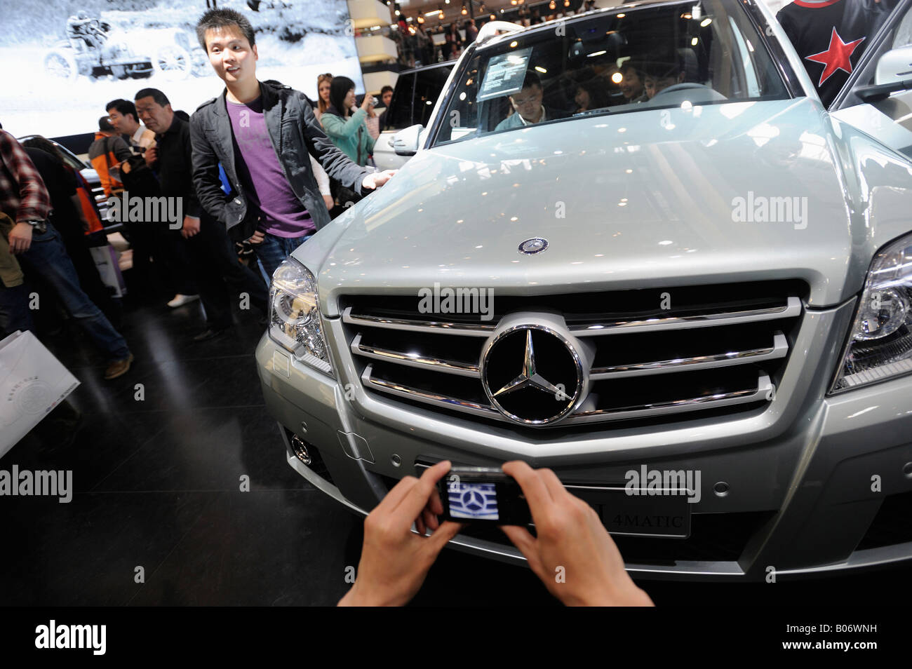 A Chinese man takes a photo with a Mercedes-Benz GLK 220 CDI at the ...
