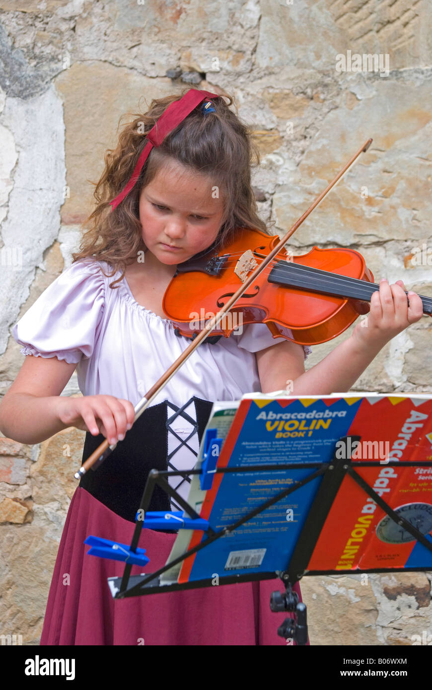 Serious young busker dressed in period costume playing a violin Stock ...