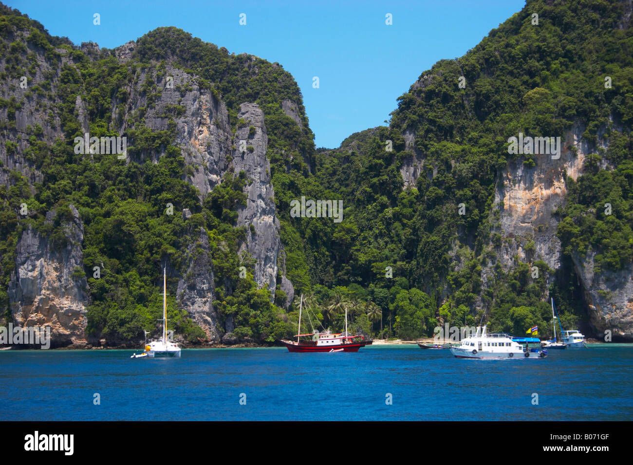 Tropical island cliffs with trees rise above waters of Andaman Sea ...