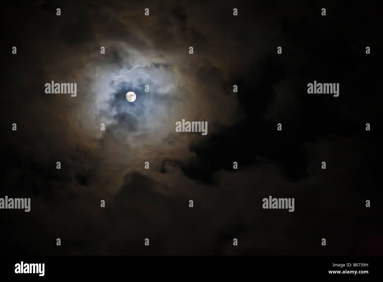 Moon behind dark clouds at night Stock Photo - Alamy