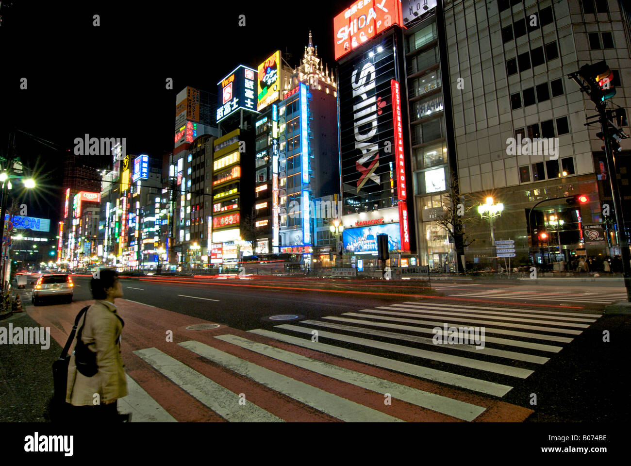 Waiting to cross at a pedsestrian crossing. Neon lit night scene ...