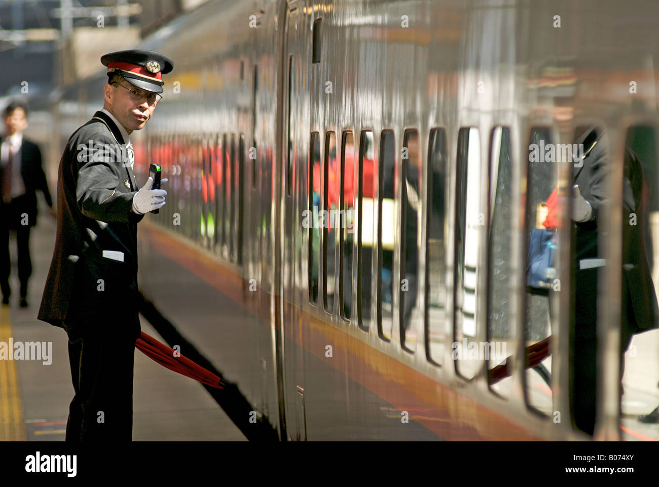 Platform guard overseeing the departure of a Shinkansen 'Bullet Train ...