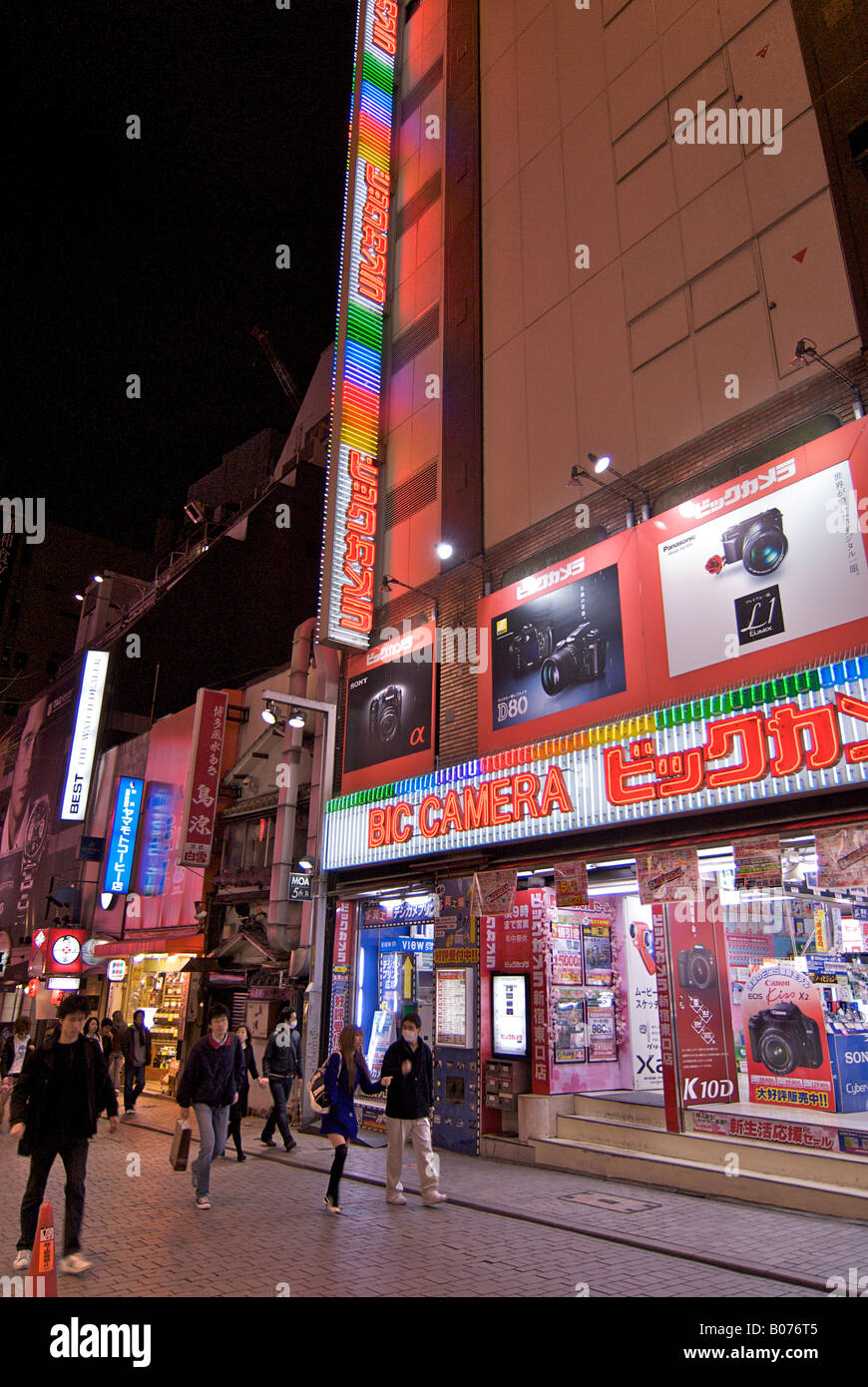 Pedestrians in the street. BIC CAMERA store. Neon lit night scene ...