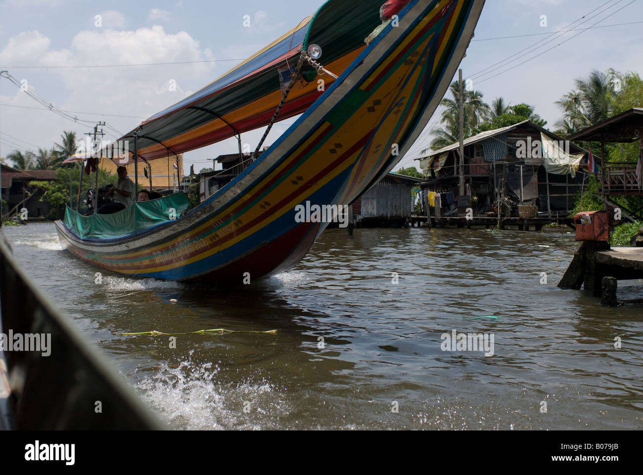 High prow speeding longtail river boat on residential canal near Chou ...