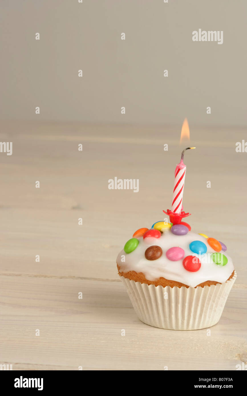 Birthday muffin with icing, sprinkles and candle Stock Photo - Alamy