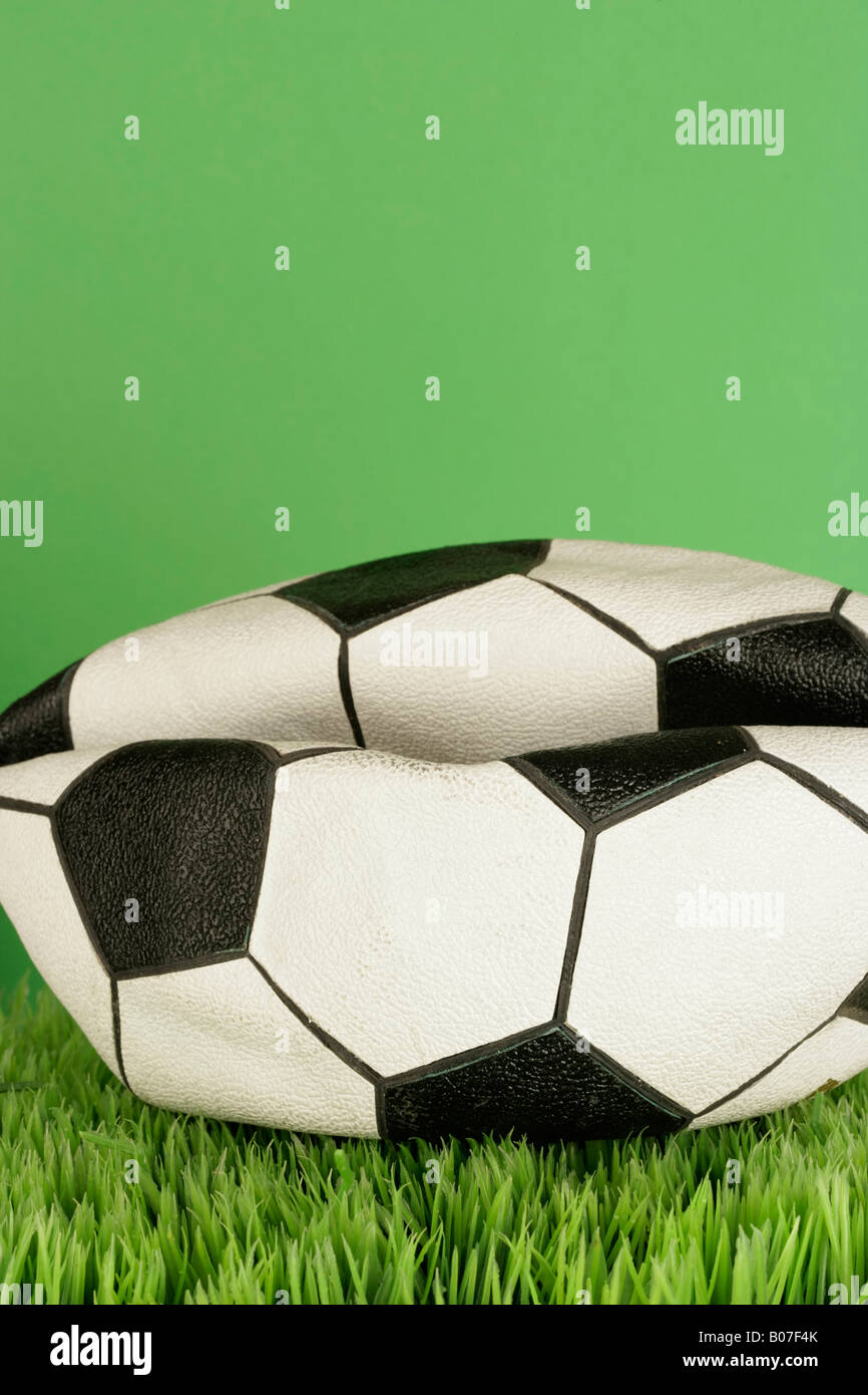 A flat football on grass Stock Photo - Alamy