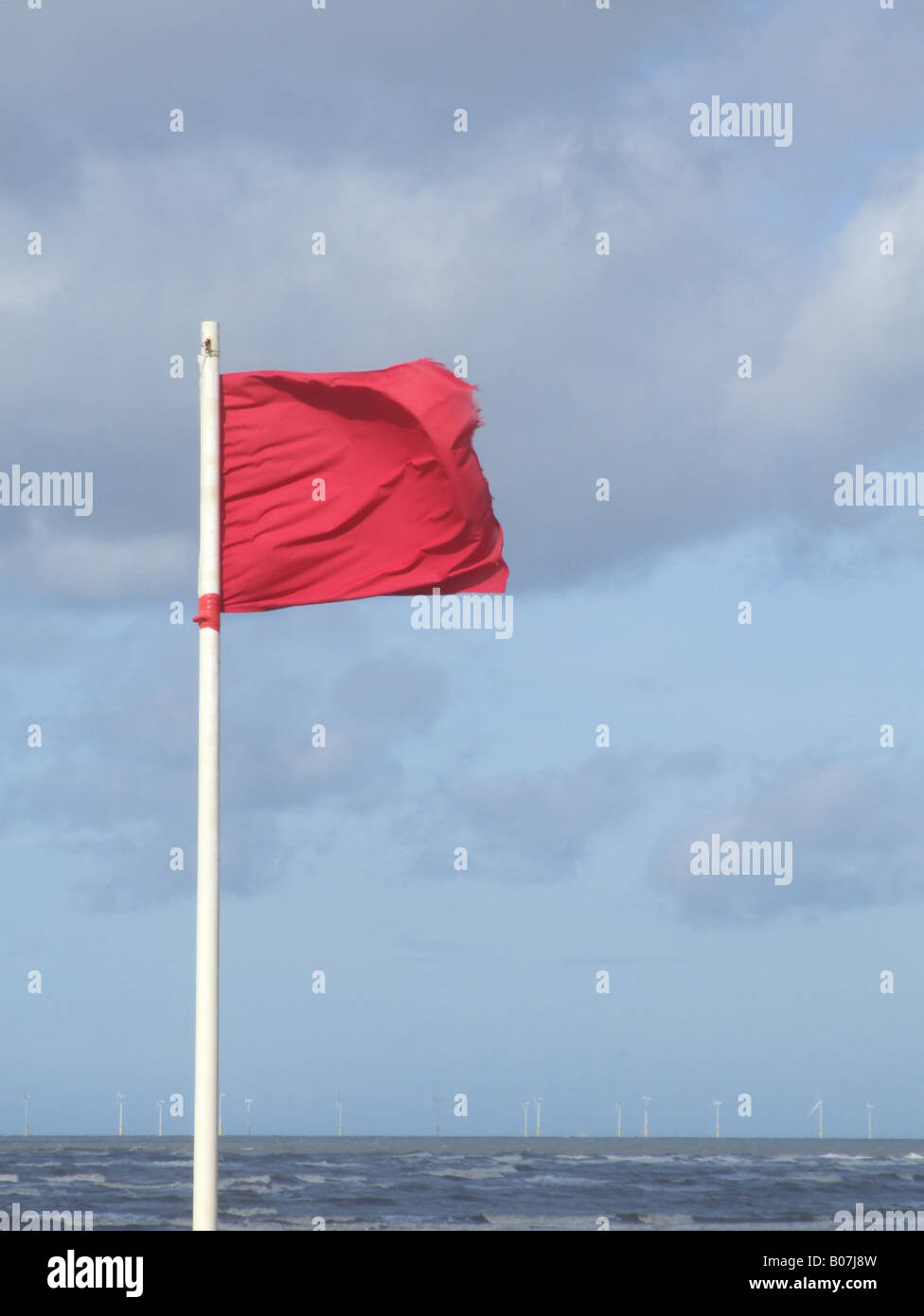 red warning flag in wind by beach Stock Photo - Alamy