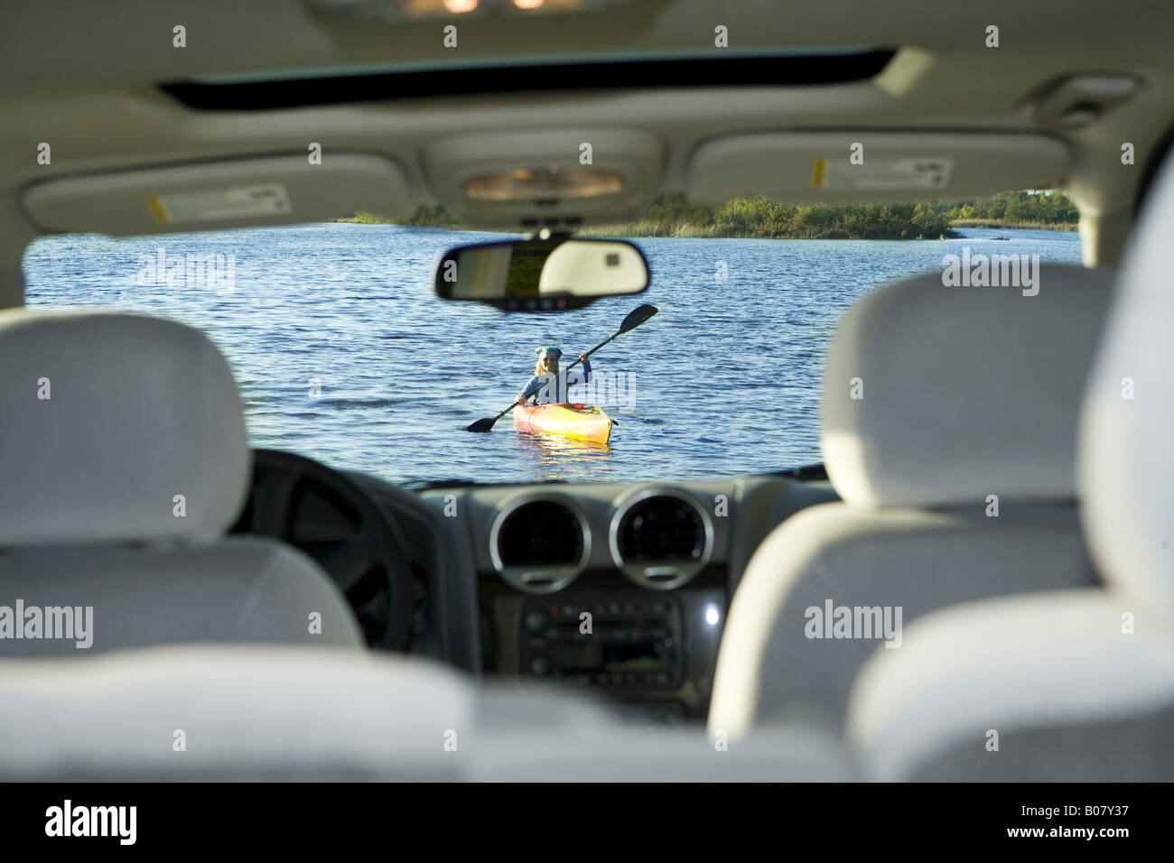 woman seen thorugh windscreen paddling her kayak towards SUV Stock ...