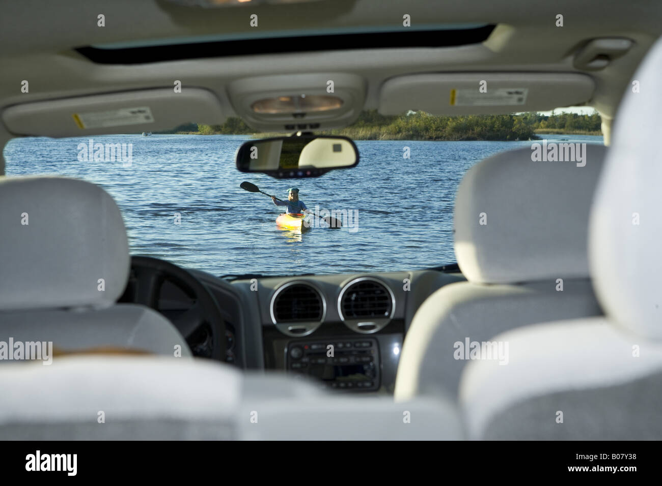 woman seen thorugh windscreen paddling her kayak towards SUV Stock ...