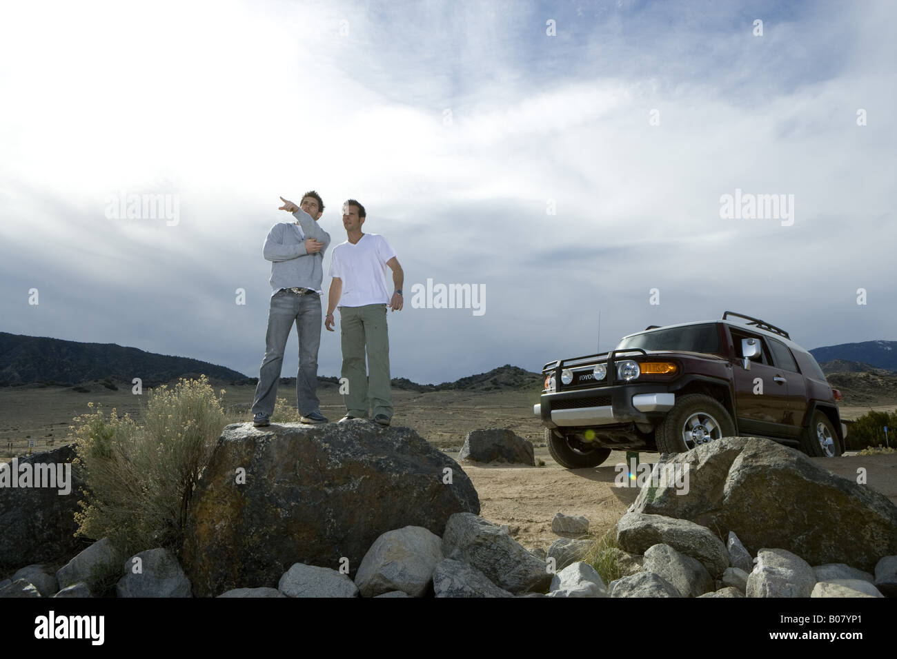 Two men stand atop large rock in California desert Stock Photo - Alamy