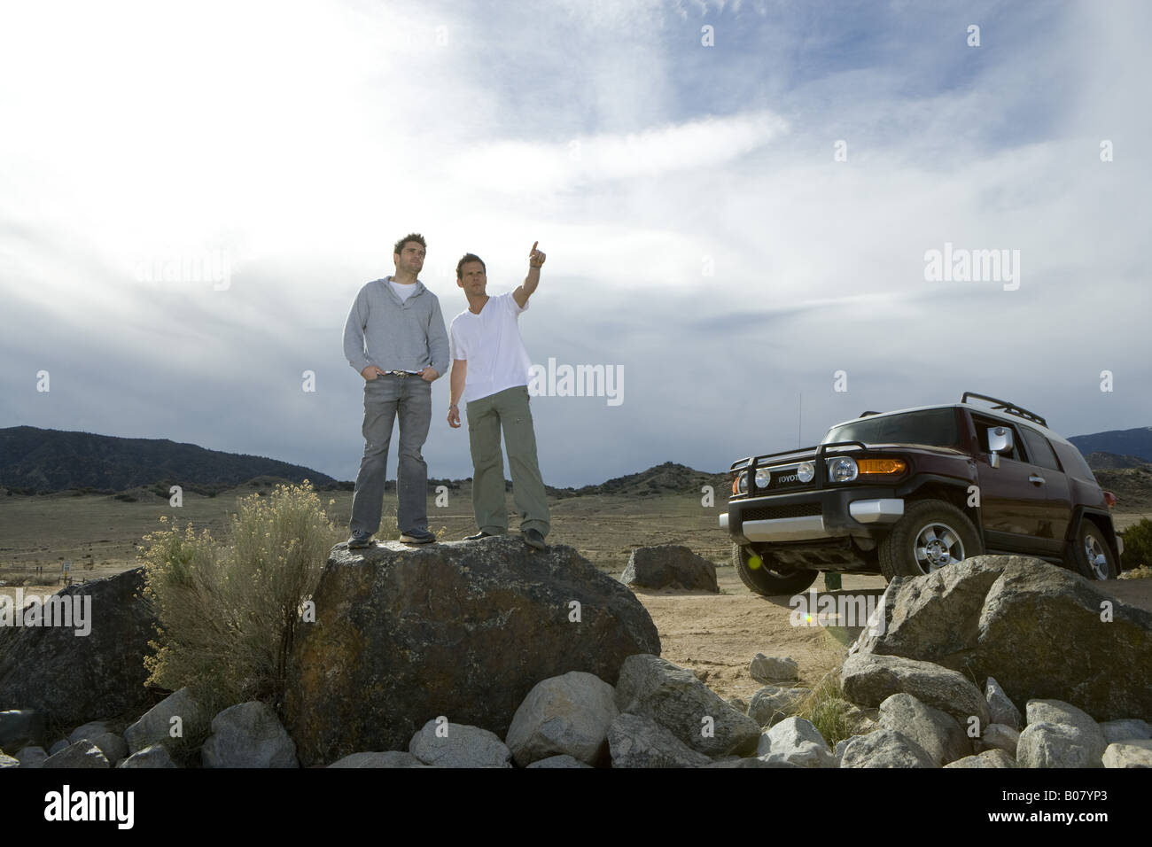 Two men stand atop large rock in California desert Stock Photo - Alamy
