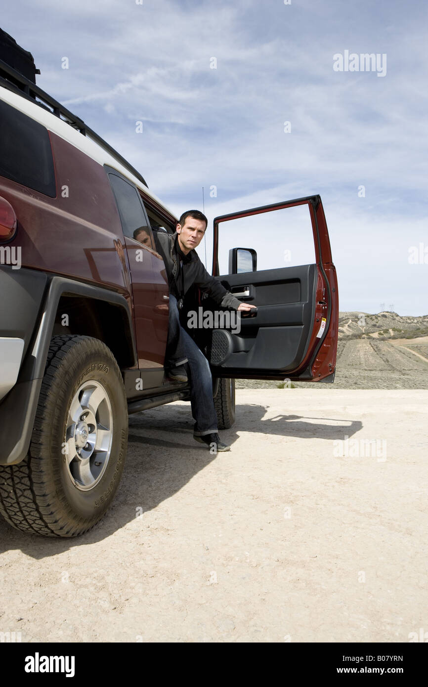 Man exiting his off-road vehicle in desert Stock Photo - Alamy