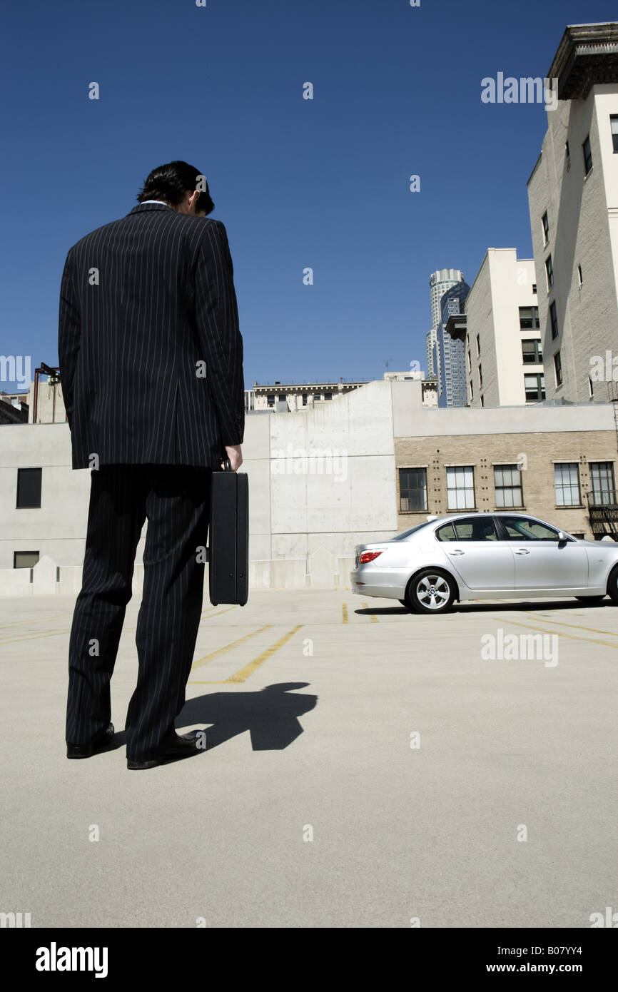 Businessman looking down at shadow on rooftop car park Stock Photo - Alamy
