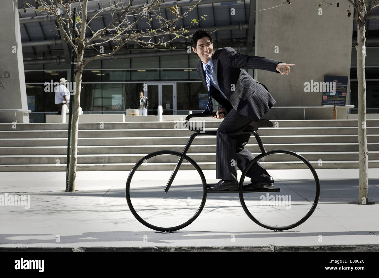 Businessman riding vintage bicycle on pavement pointing left Stock ...
