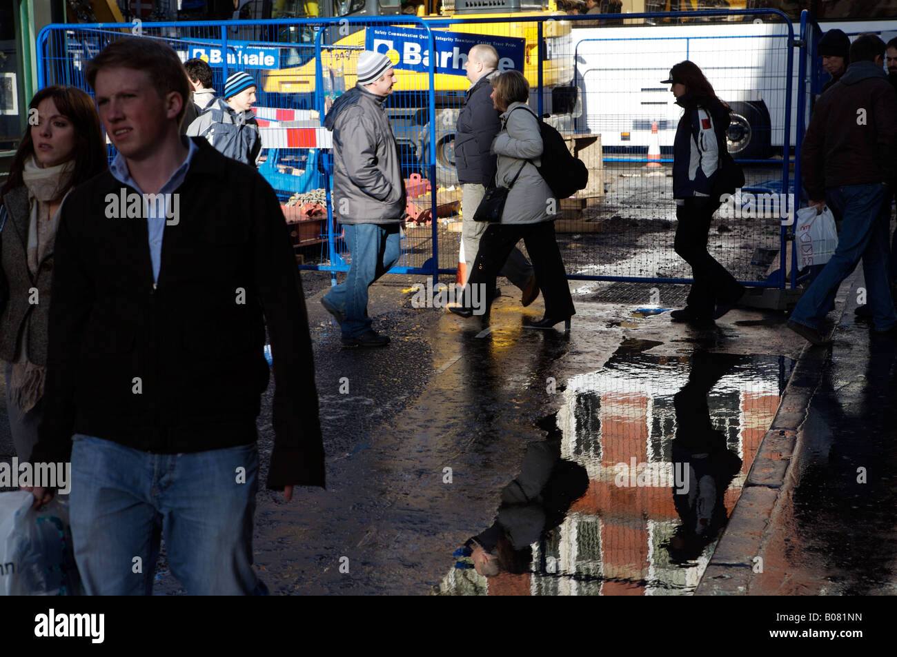 a street scene in london with a pedestrian jumping over a deep puddle ...