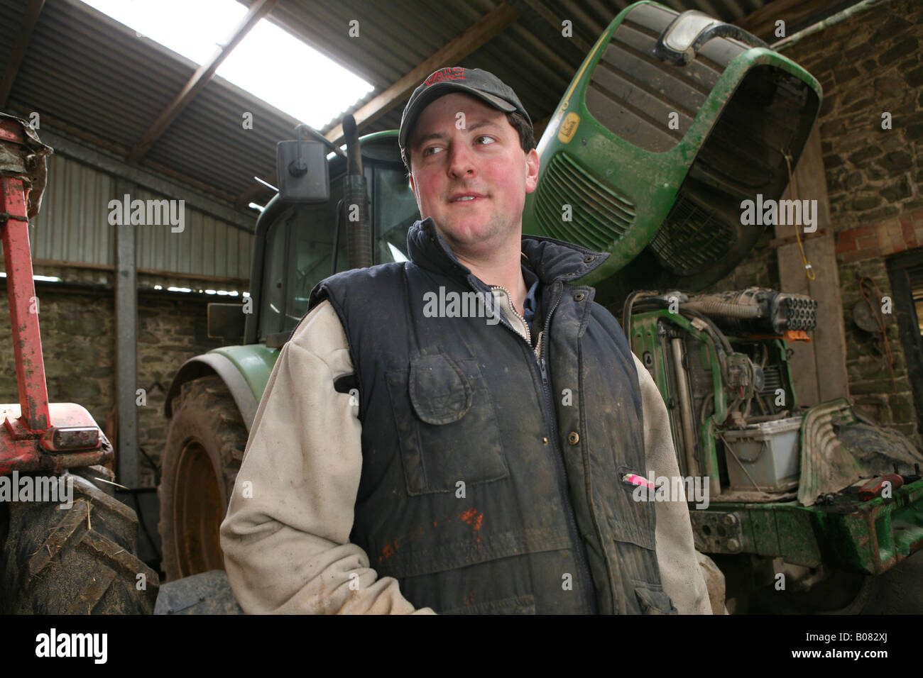 a portarit of a young farmer in north devon stood next to his farming ...