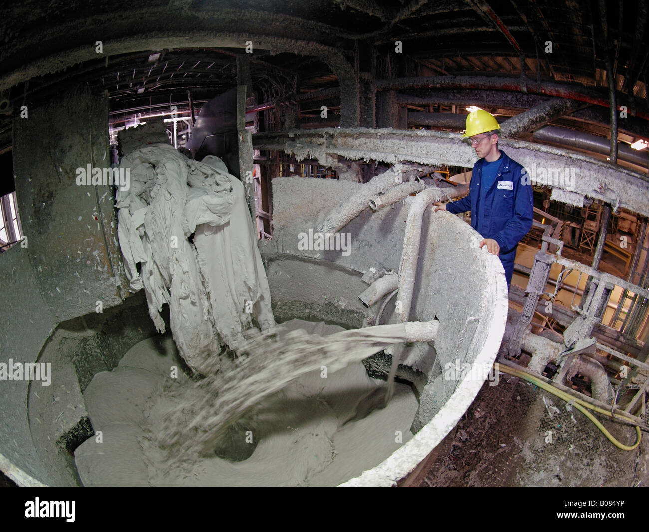 Man standing next to large machine where old waste paper is shredded ...