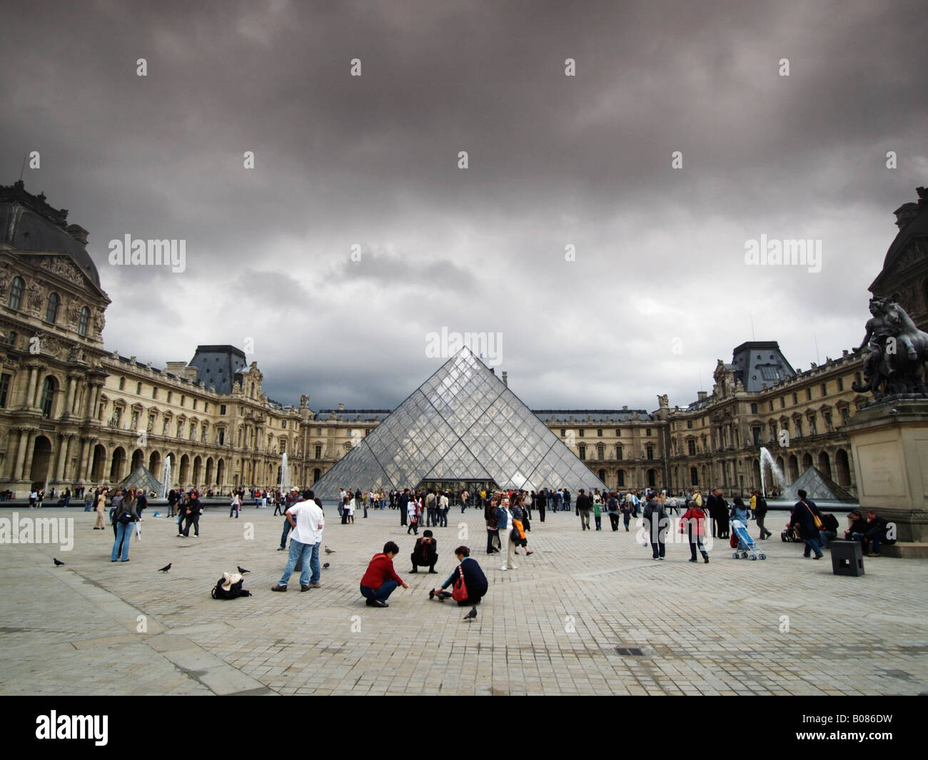 Louvre courtyard with many people tourists and the pyramid by I M Pei ...