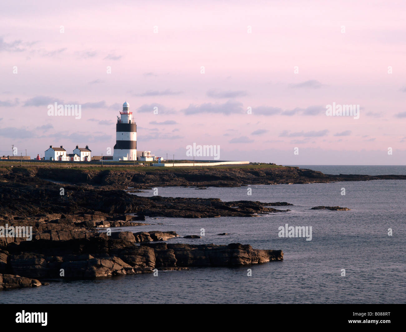HOOK LIGHTHOUSE rocky coast and pink sky . The oldest in Ireland and ...