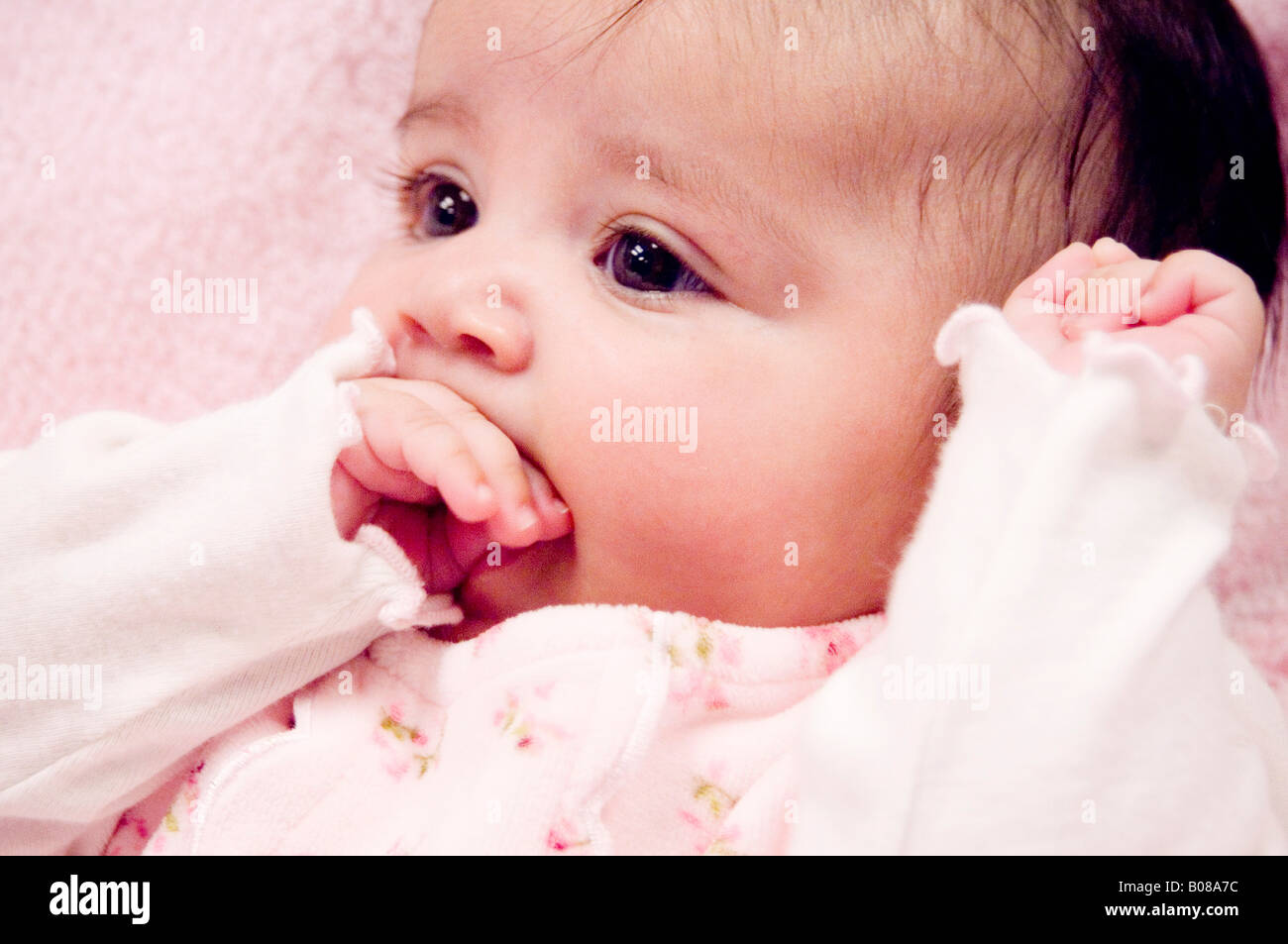 Baby with hand in mouth Stock Photo - Alamy
