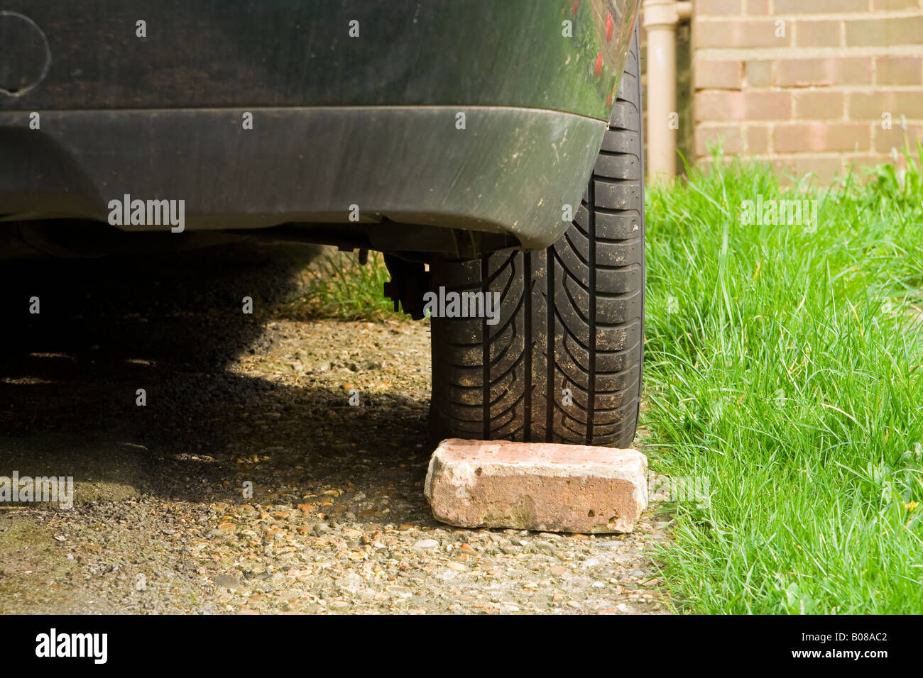 A brick behind a car wheel, UK Stock Photo - Alamy