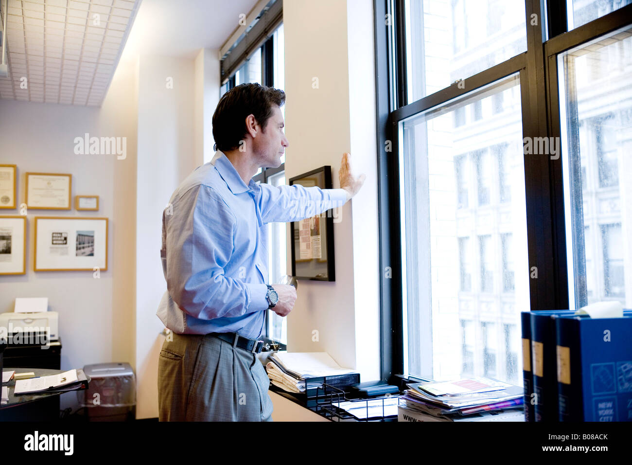 Businessman looking out office window Stock Photo - Alamy
