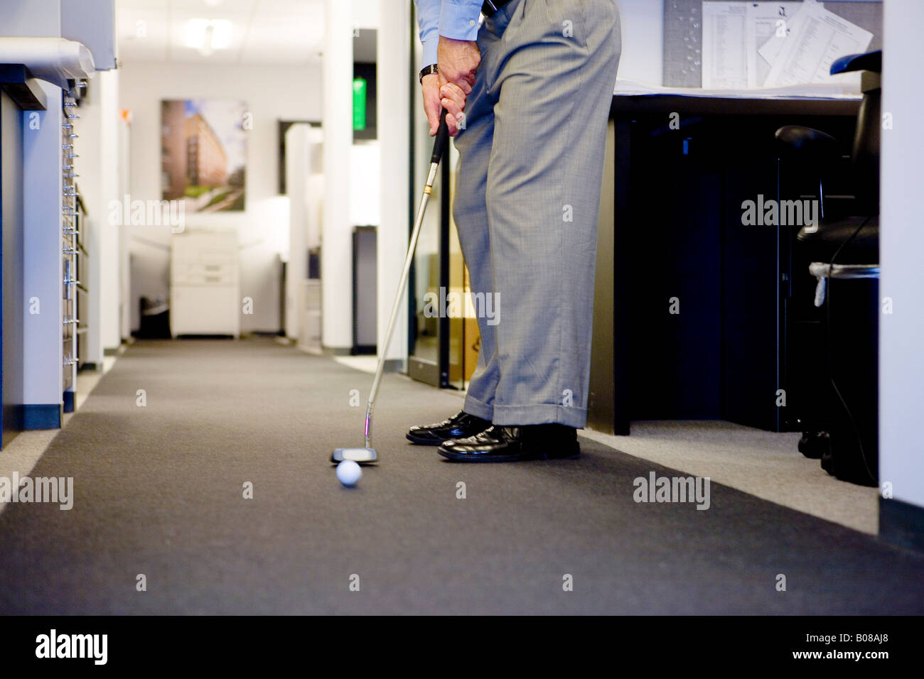 Businessman playing golf in office Stock Photo - Alamy