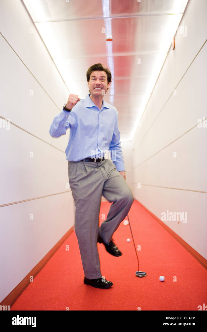 Businessman playing golf in office hallway Stock Photo - Alamy