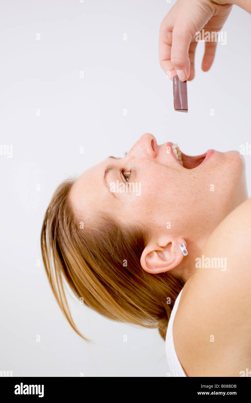 Woman dropping chocolate candy in her mouth Stock Photo - Alamy