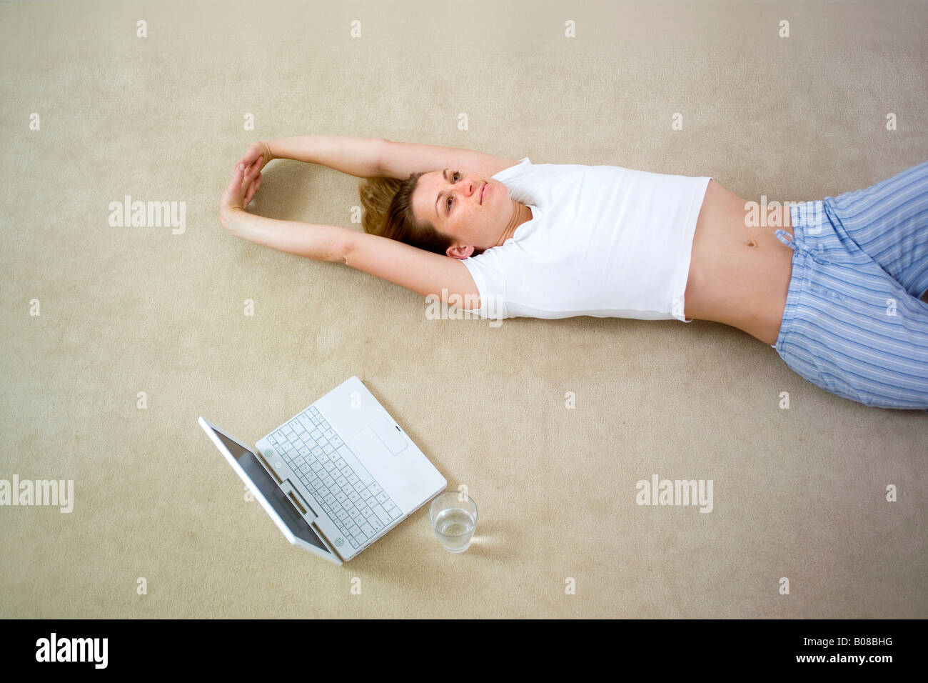 Woman stretching near computer on the floor Stock Photo - Alamy