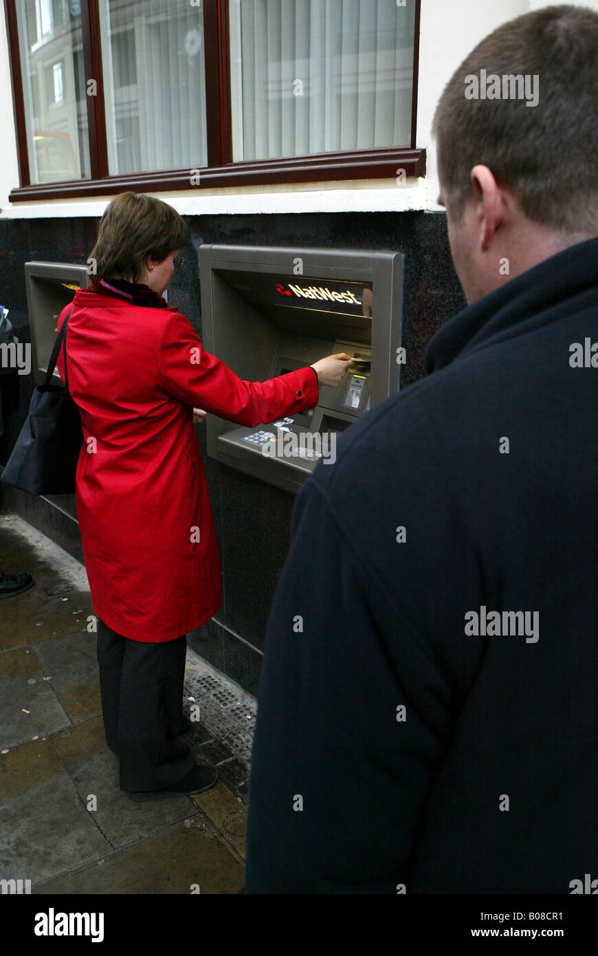 ATM Cash Machine scam. Man watches a woman inserting her card into the ...