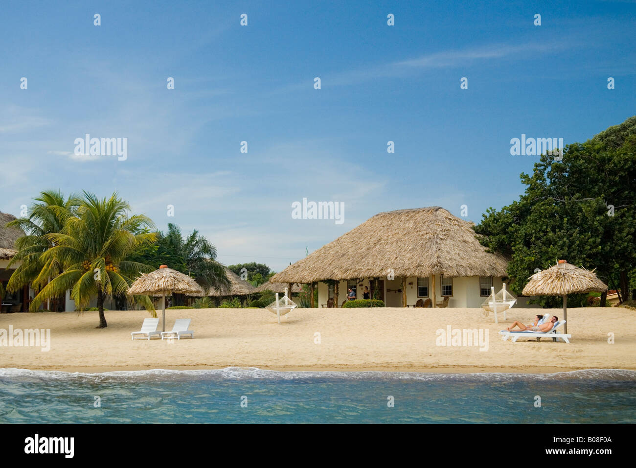 Thatched palapas, cabana and lounge chairs on beach, viewed from ...