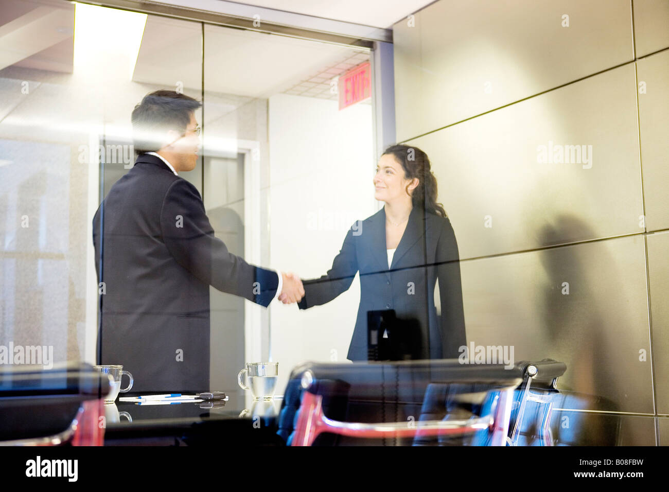 Businessman and woman in conference room shaking hands Stock Photo - Alamy