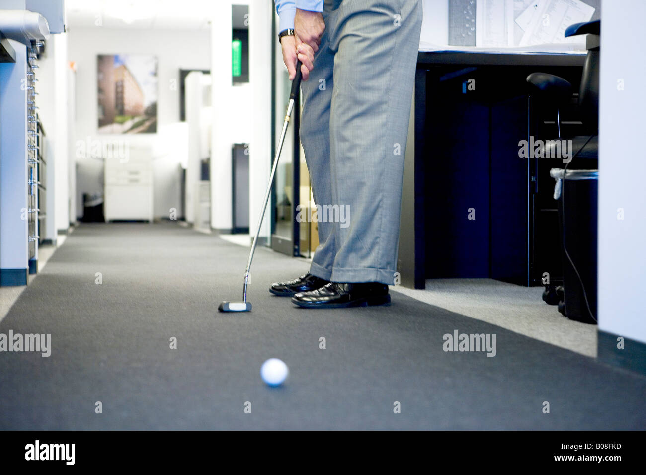 Businessman playing golf in office Stock Photo - Alamy