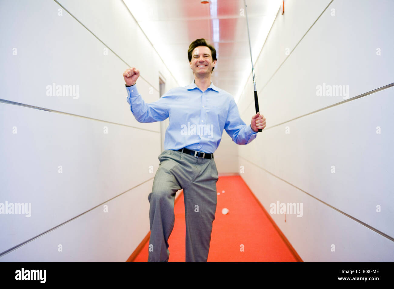 Businessman playing golf in office hallway Stock Photo - Alamy
