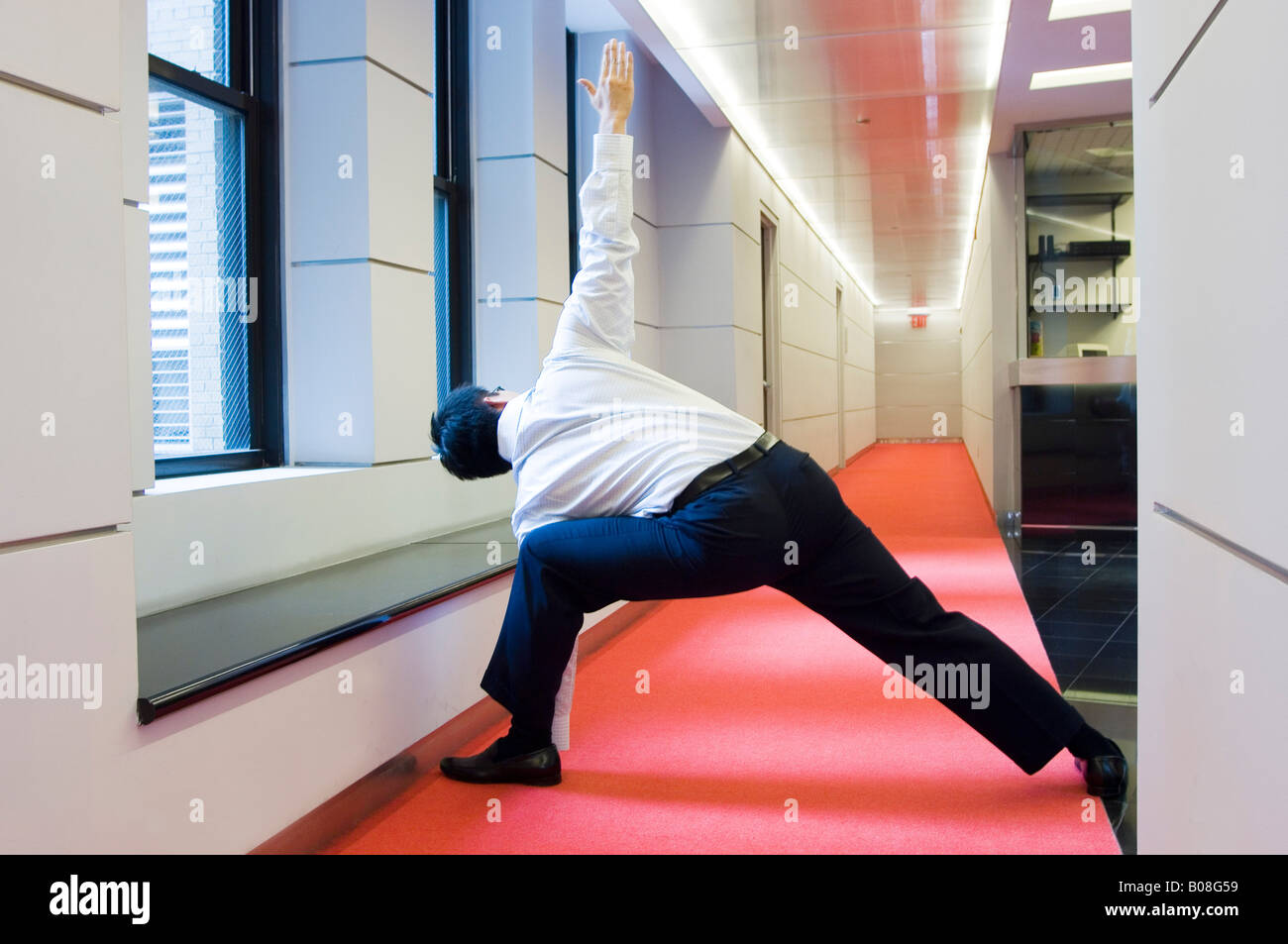 Businessman in hallway stretching Stock Photo - Alamy