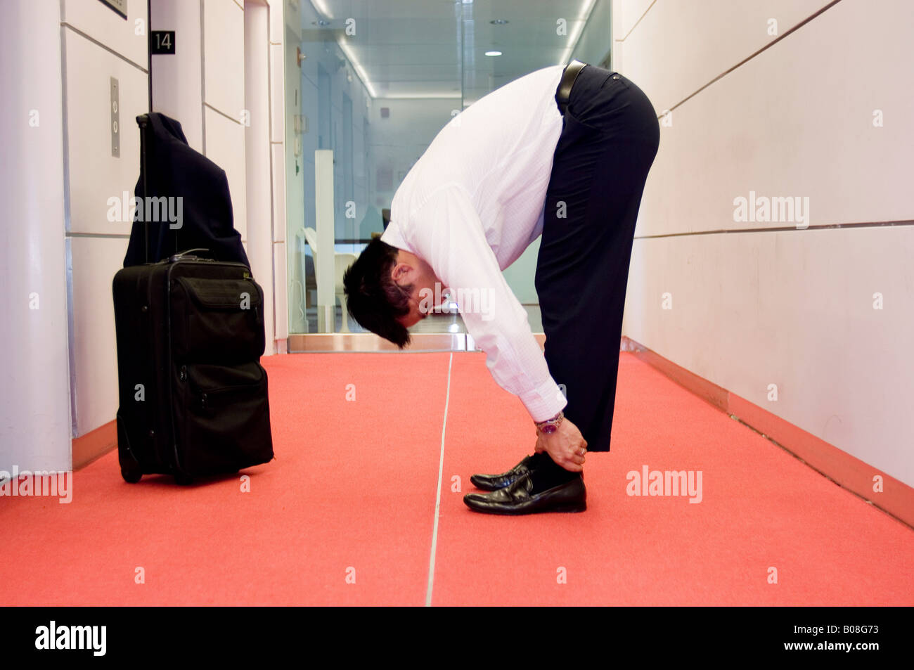 Businessman stretching in hallway Stock Photo - Alamy