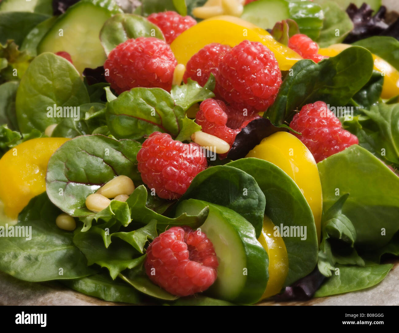 A fresh tossed salad with spinach misc vegetables rasberries and pine ...