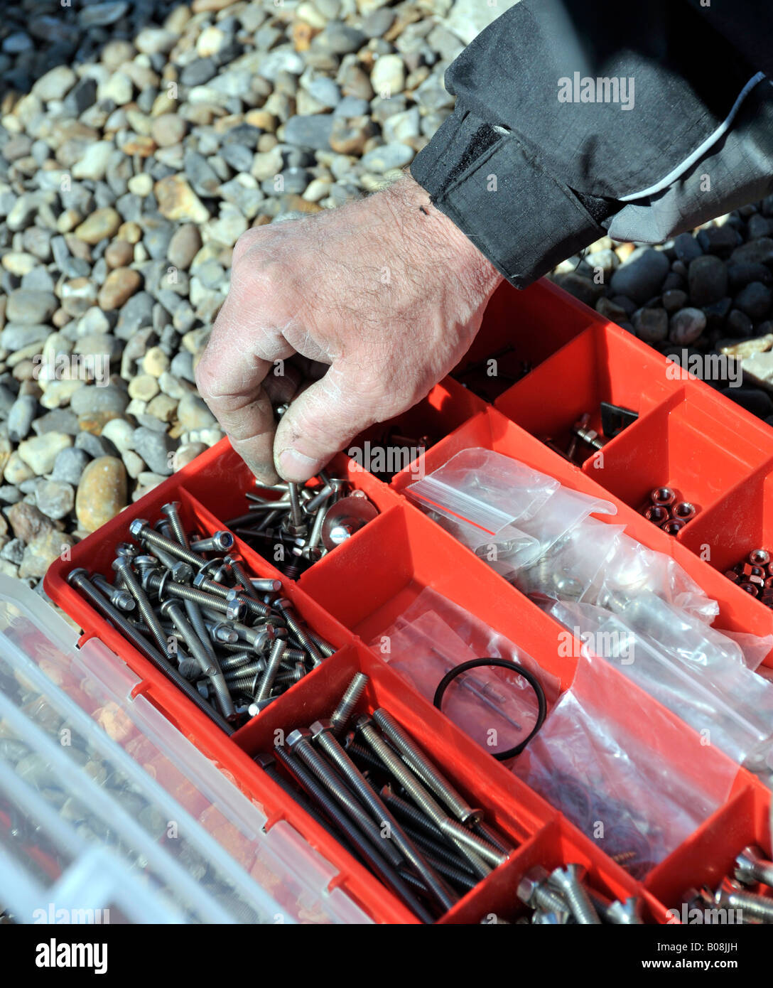 mans hand selecting stainless steel screw from storage box Stock Photo ...