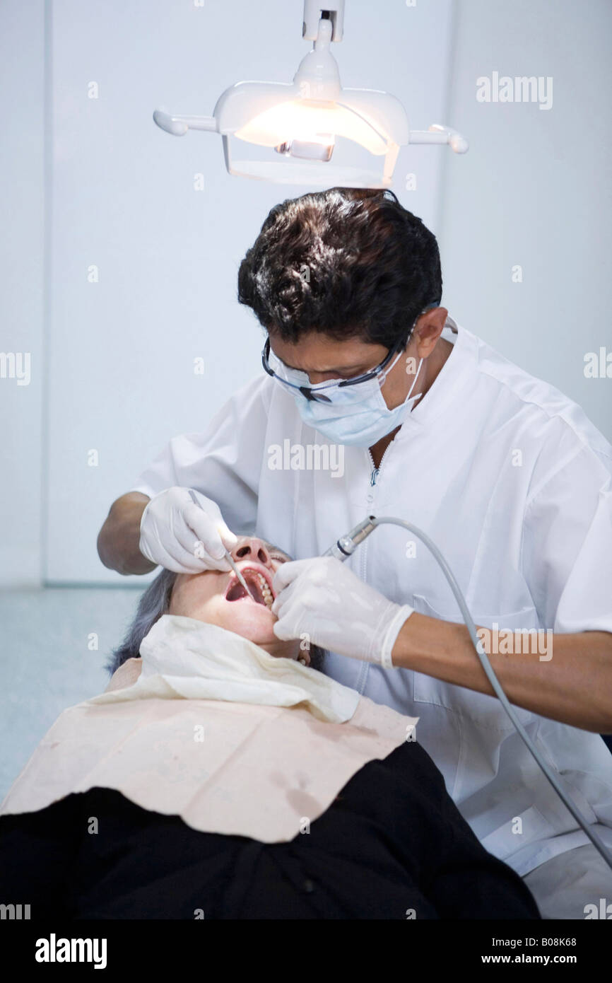 Dentist performing dental examination hi-res stock photography and ...