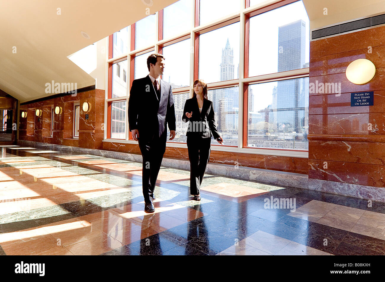 Businessman and businesswoman walking hallway Stock Photo - Alamy