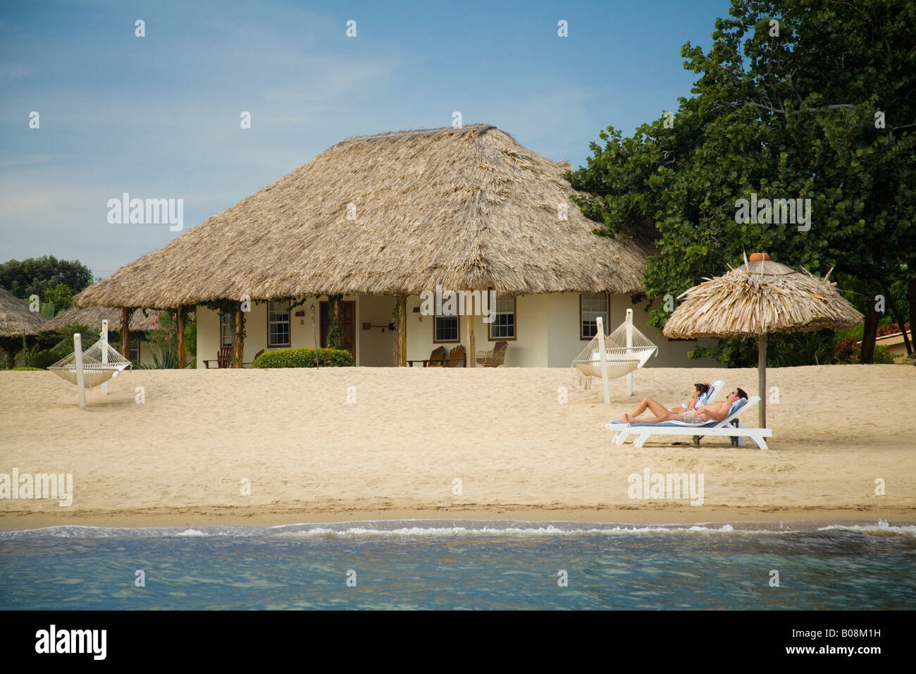 Thatched palapas, cabana and lounge chairs on beach, viewed from ...