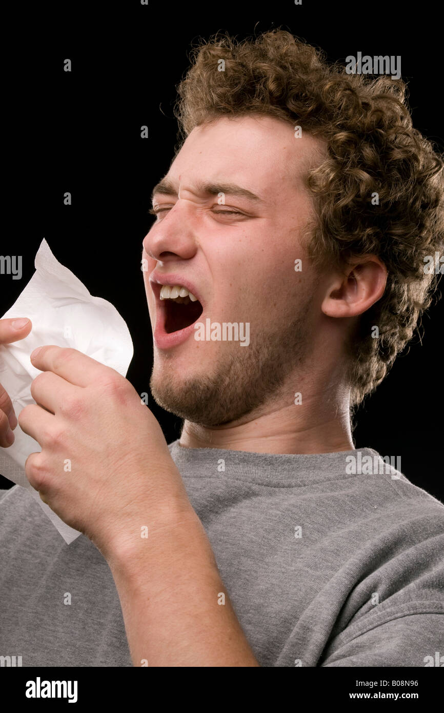 Young man sneezing Stock Photo - Alamy