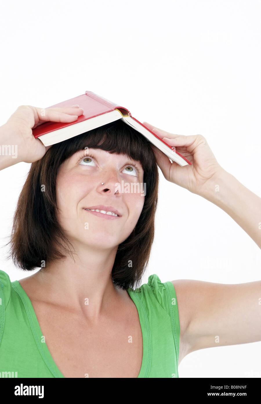 brown-haired woman in a green t-shirt, with a book on her head Stock ...