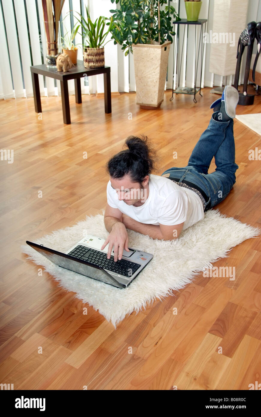 young man with laptop, lying on the floor in the living room Stock ...