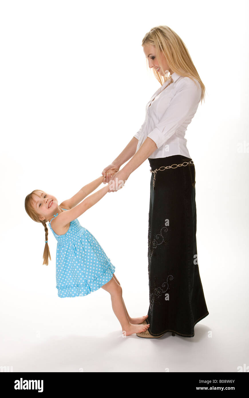 Full length view of pretty four year old girl standing on mom's feet ...
